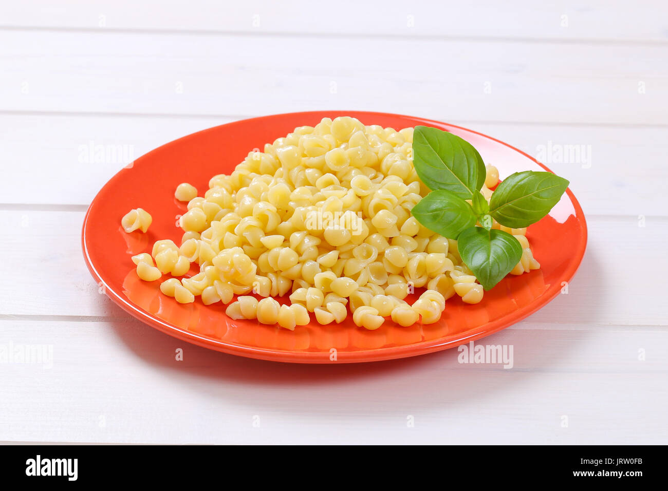 plate of small pasta shells on white wooden background Stock Photo - Alamy