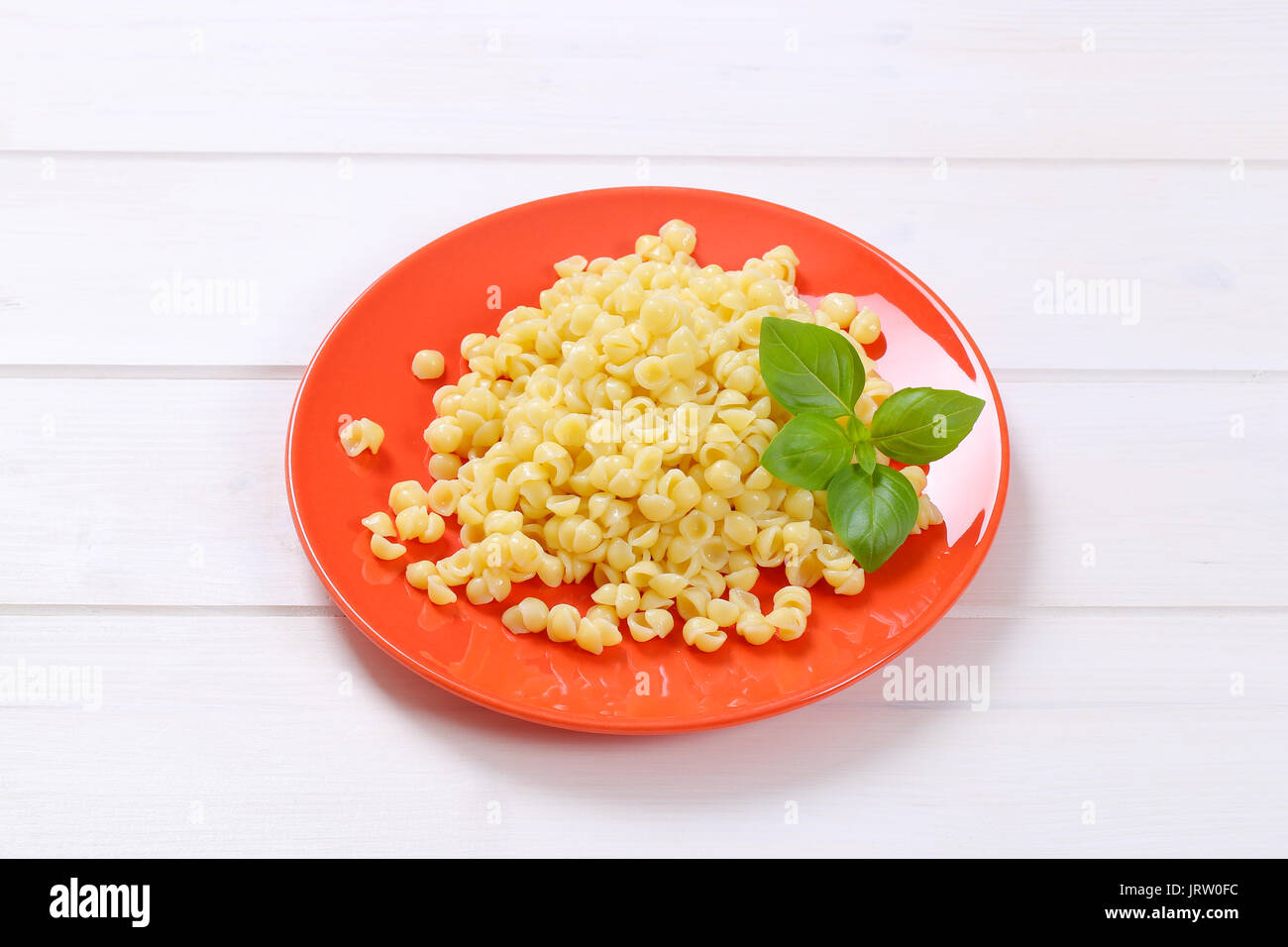 plate of small pasta shells on white wooden background Stock Photo - Alamy