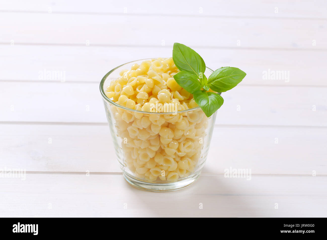glass of small pasta shells on white wooden background Stock Photo - Alamy