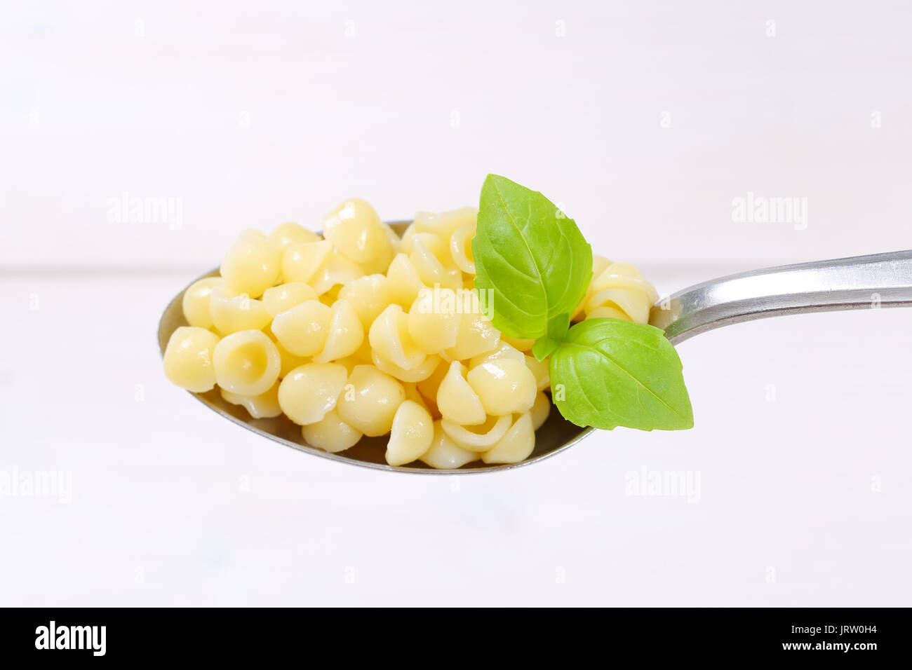spoon of small pasta shells on white wooden background Stock Photo - Alamy