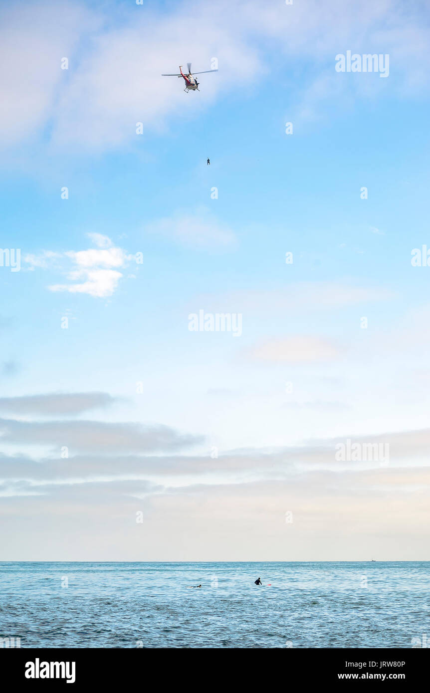US coastguard helicopter in flight with the ocean and lonesome surfer ...