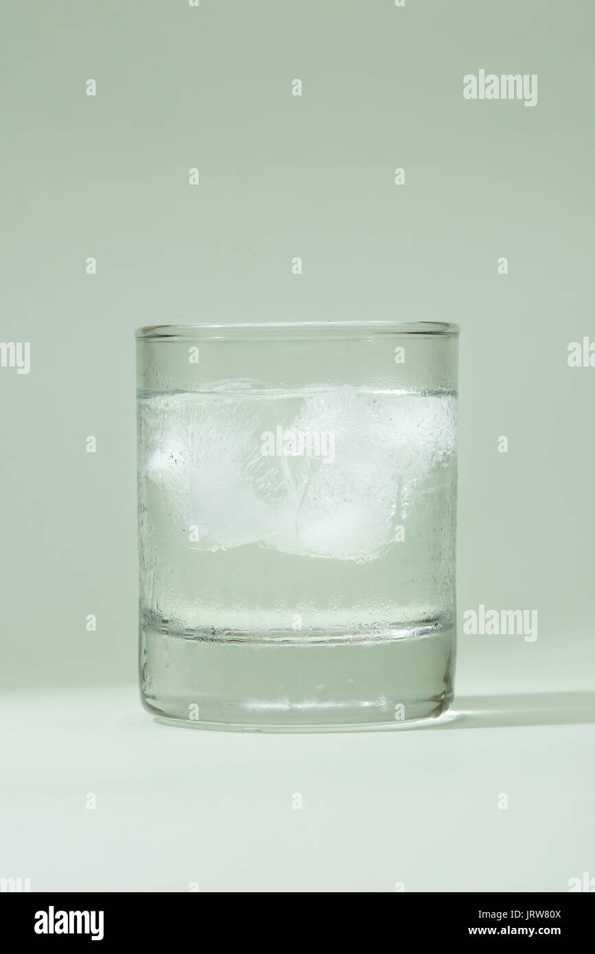 Ice drinking water glass on table over green Stock Photo - Alamy