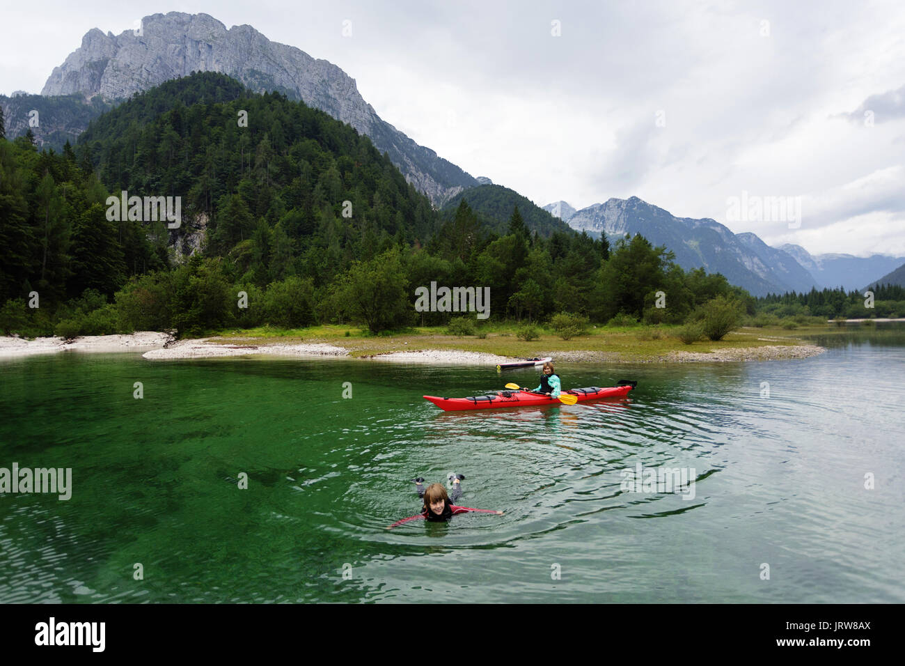Mother in kayak looking at her son playing in the emerald green water ...
