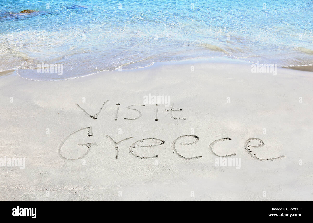 visit greece written on sand - greek summer photos Stock Photo - Alamy