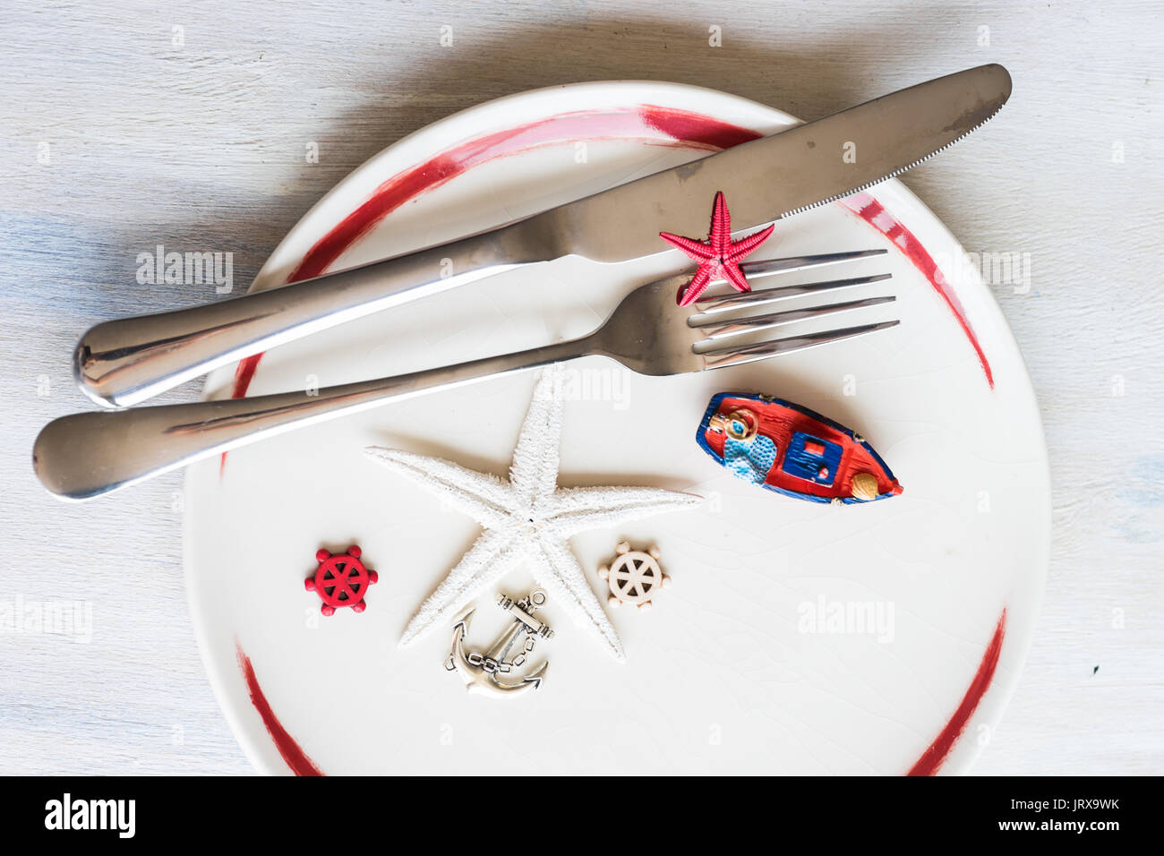 Summer vacation marine table setting with rustic plates and silverware ...