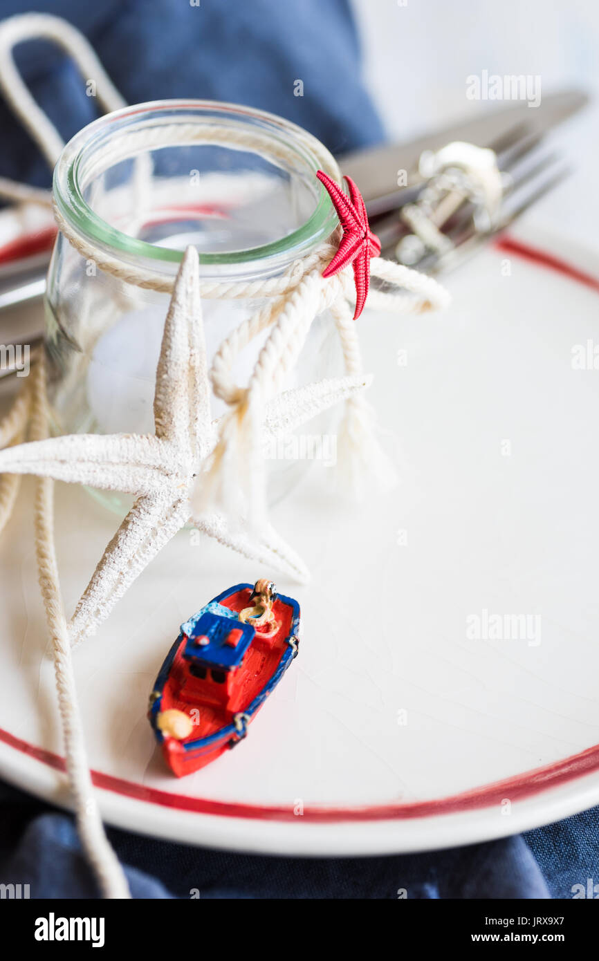 Summer vacation marine table setting with rustic plates and silverware ...