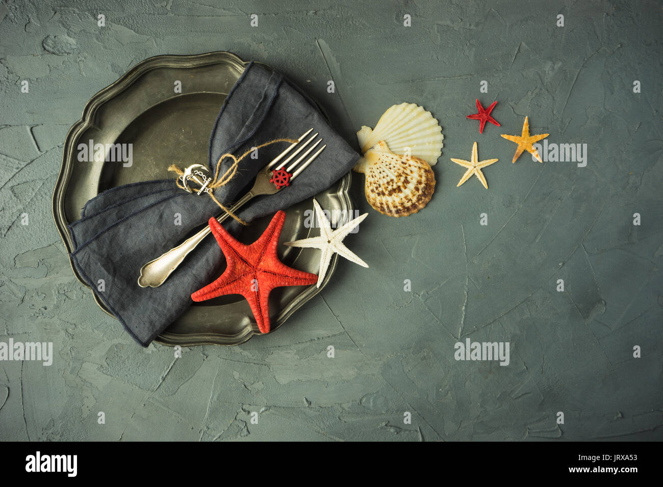 Summer vacation marine table setting with rustic plates and silverware ...