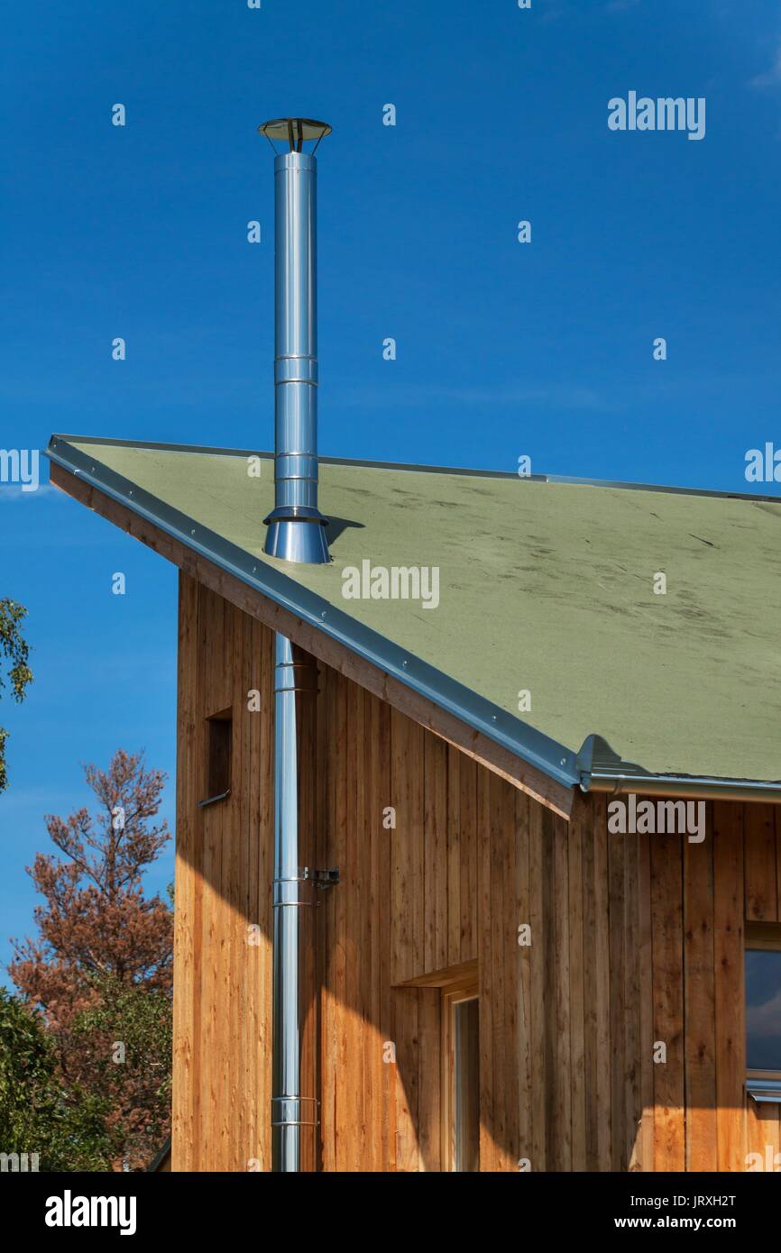Stainless steel chimney on an organic wooden building near the forest ...