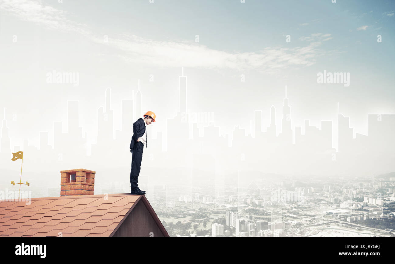 Engineer man standing on roof and looking down. Mixed media Stock Photo ...