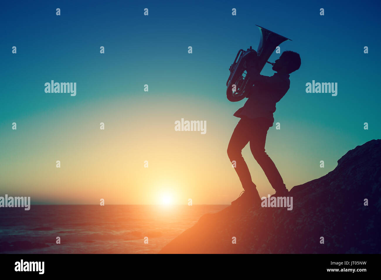 Silhouette at sunset of a musician play Tuba musical instrument on sea ...