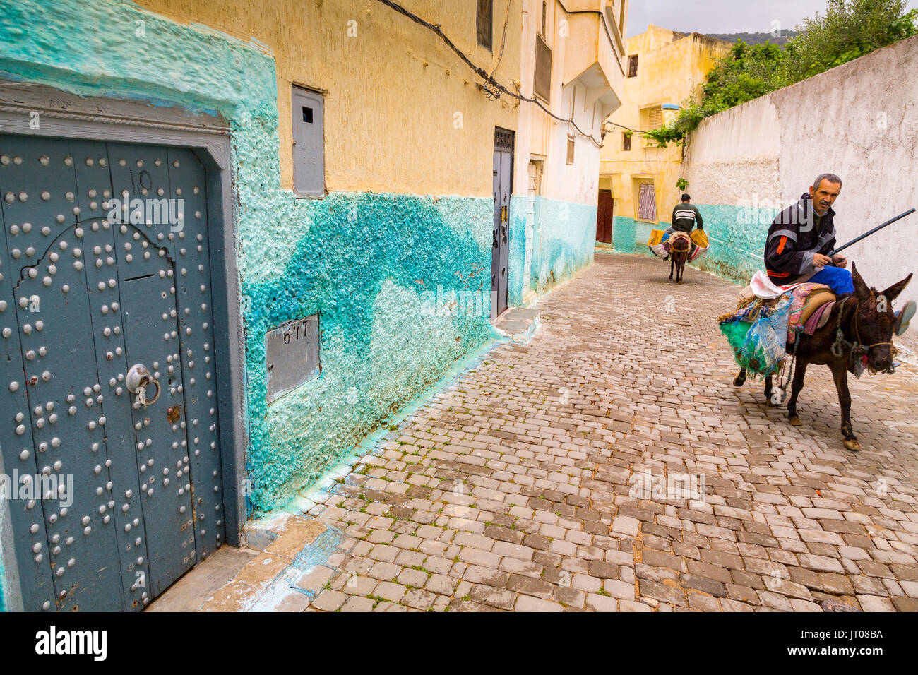 Traditional blue door of a house. Man riding a donkey, Street life ...