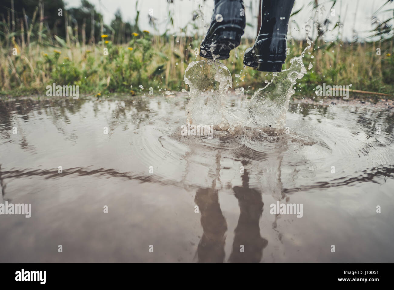 close-up of young woman's legs with rubber boots jumping and dancing in ...
