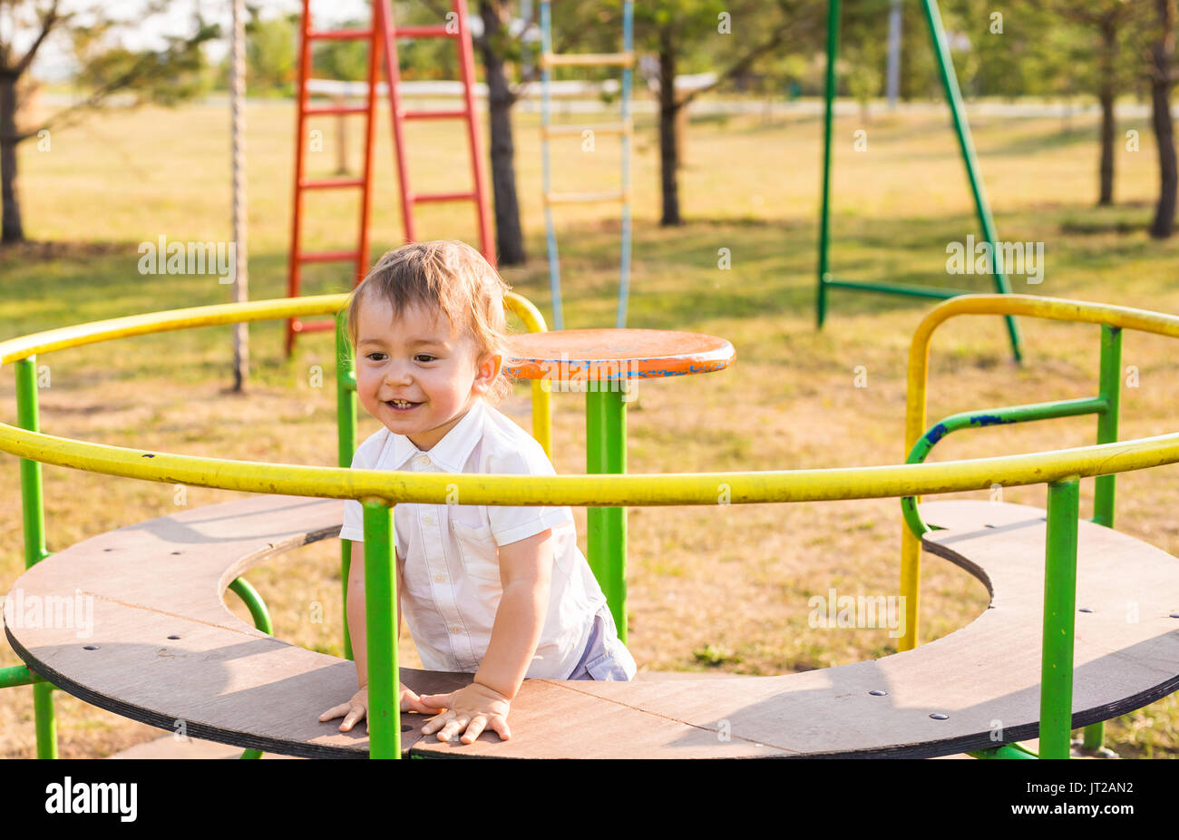 playful child with parents at the playground outdoor. Mom, dad and ...