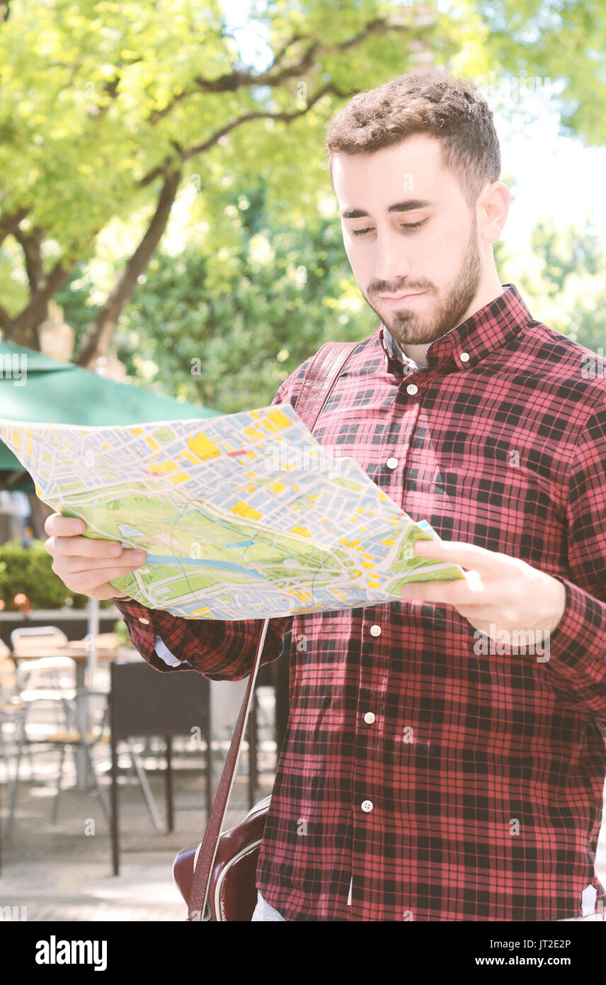 Portrait of a young handsome tourist man looking at a map. Tourism ...