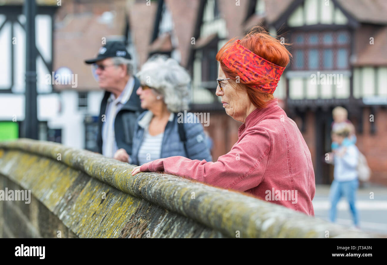 People standing on a bridge looking over at the river below, in Arundel ...