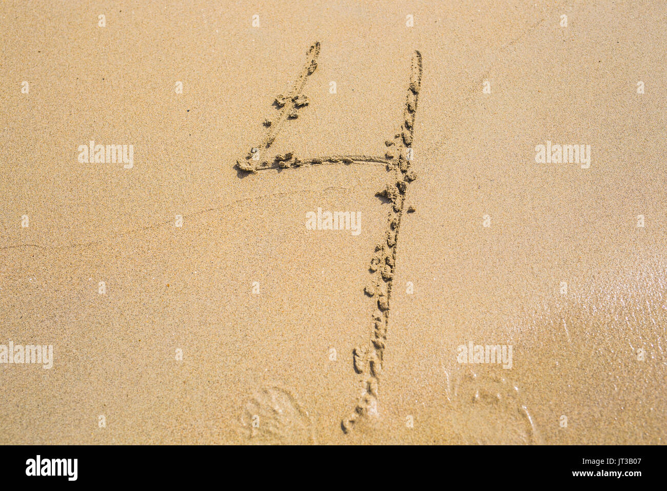 The number four drawn on sand at the beach, holiday concept background ...