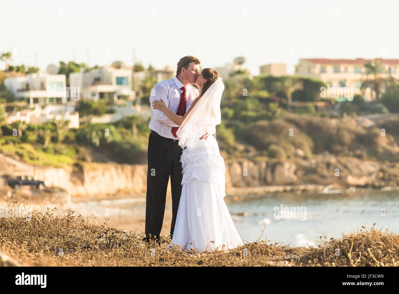 The full-length view of the groom hugging the bride back and kissing in ...