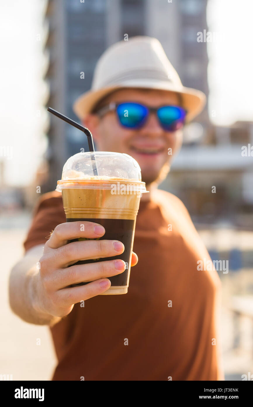 Young happy smiling man holding a cup of coffee on the city. Coffee ...