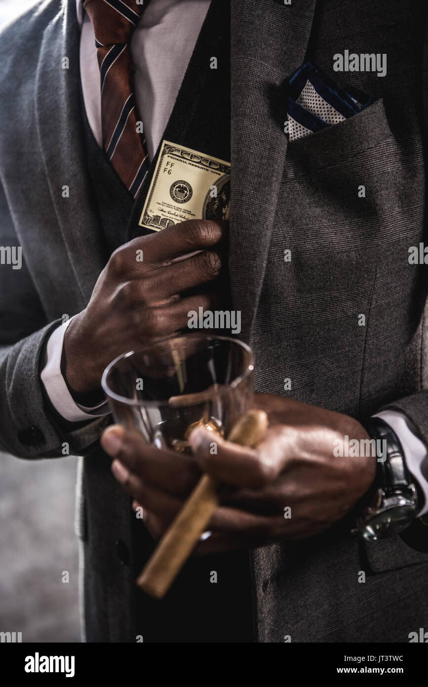 Close-up partial view of african american businessman holding glass of ... Close-up partial view of african american businessman holding glass of ...