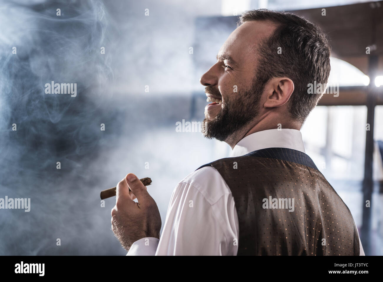 Side view of smiling confident man smoking cigar indoors Stock Photo ...