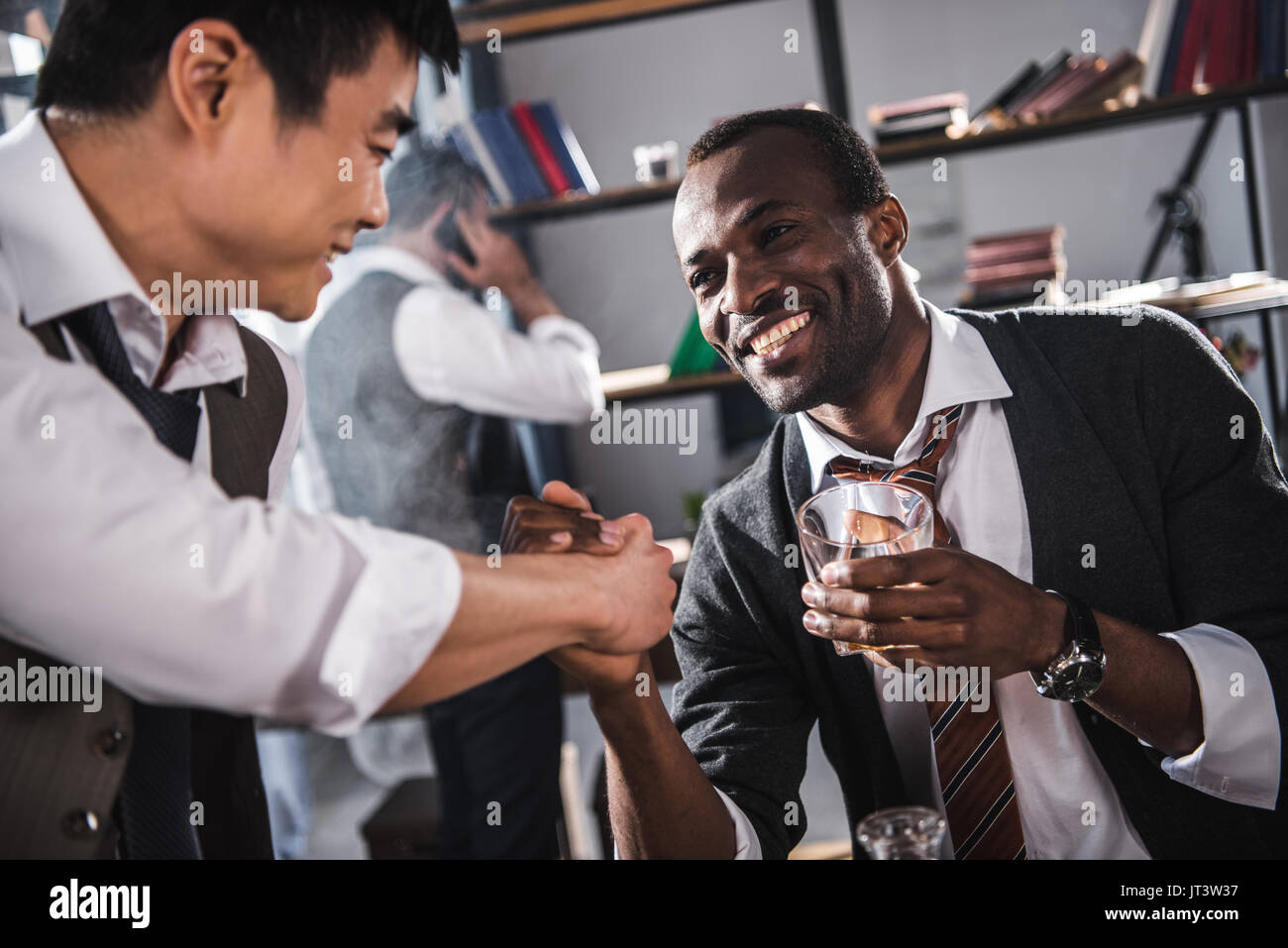 cheerful colleagues drinking alcohol while spending time together after ...