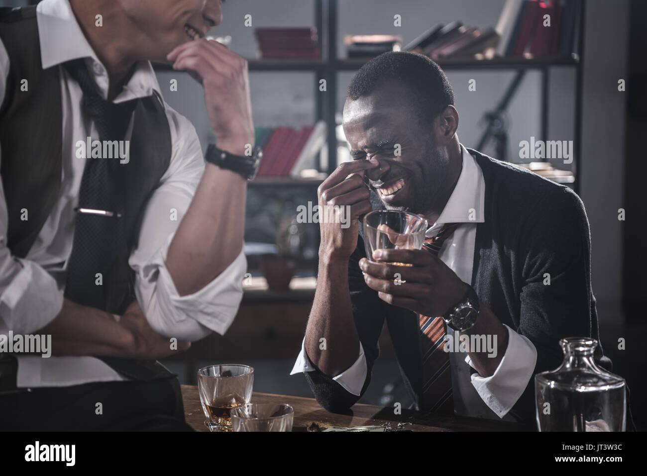 cheerful colleagues drinking alcohol while spending time together after ...