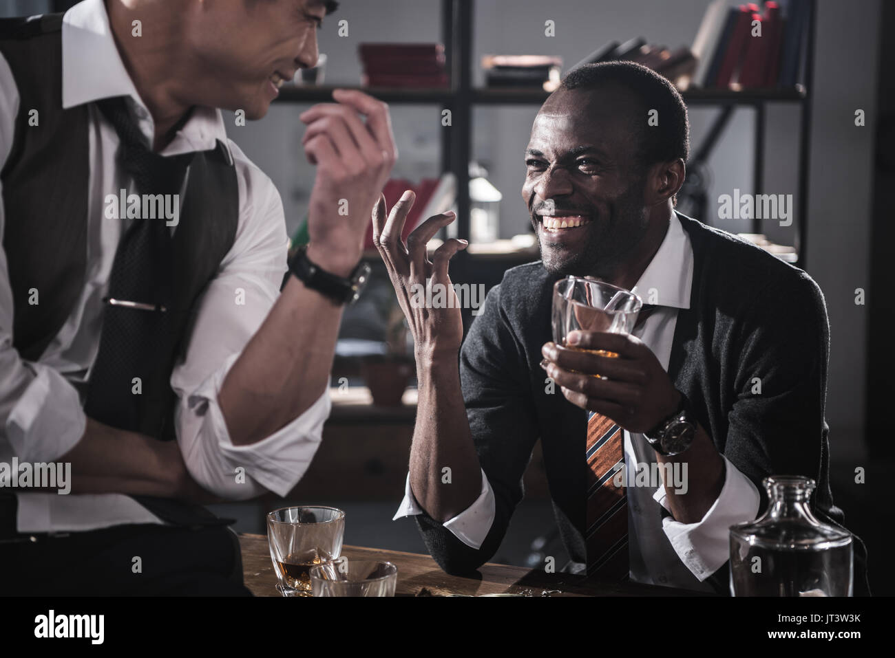 cheerful colleagues drinking alcohol while spending time together after ...