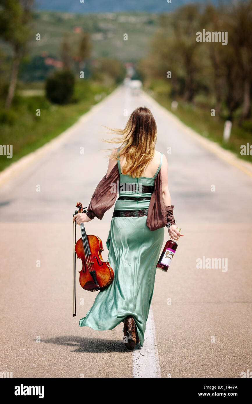 Beautiful female viola player walking along the highway Stock Photo - Alamy
