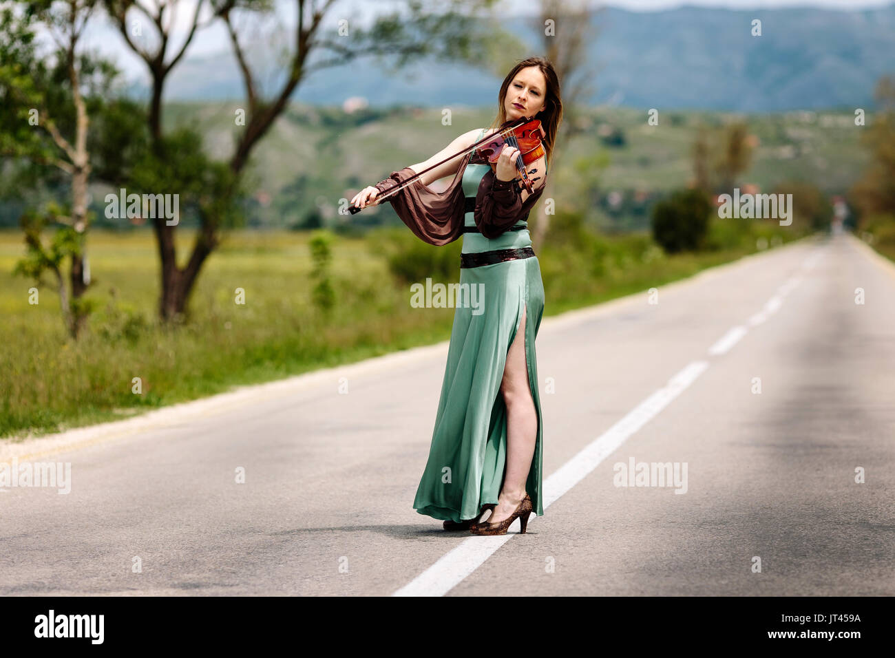 Beautiful female viola player walking along the highway Stock Photo - Alamy