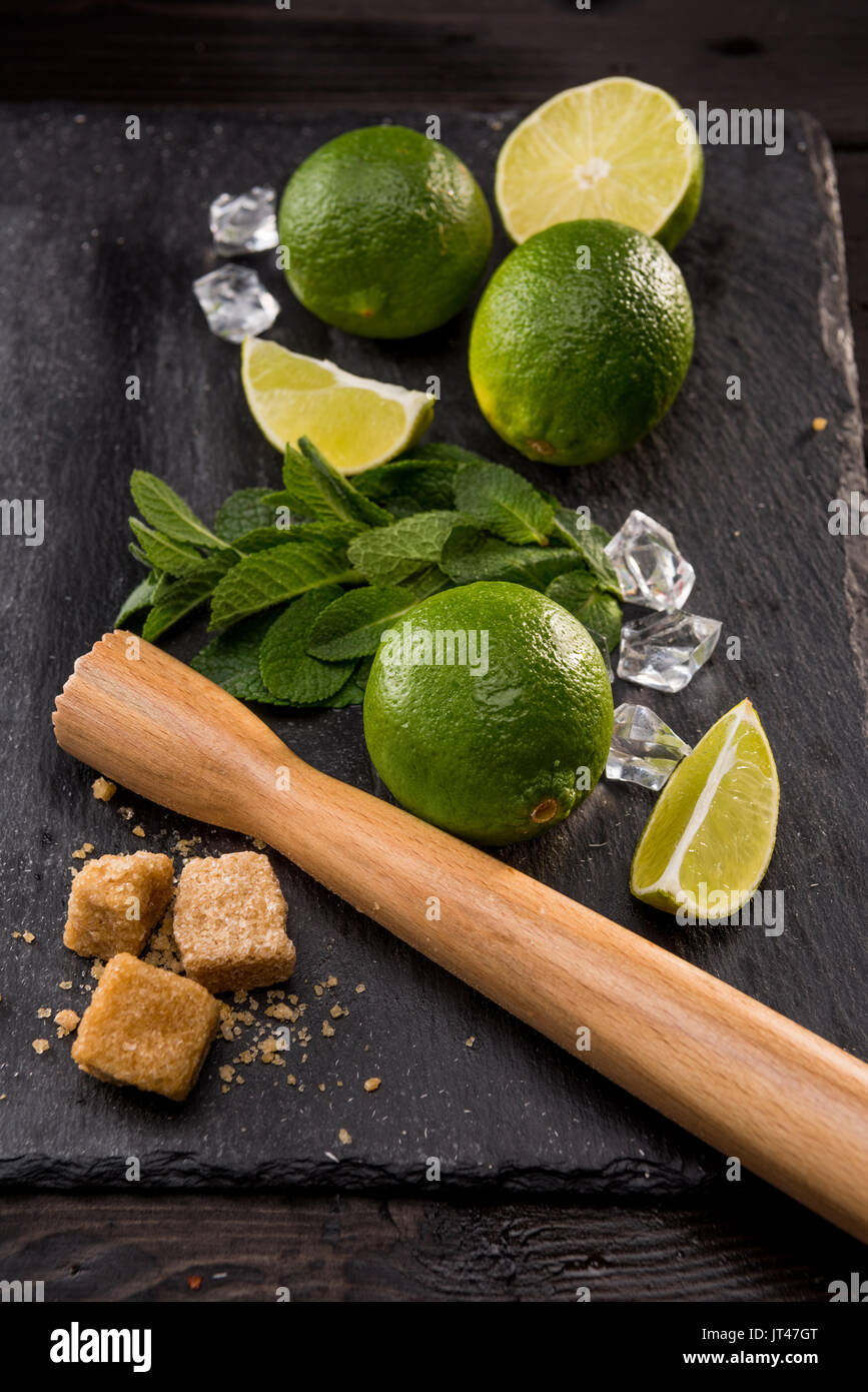 lime slices with brown sugar and wooden squeezer on stone board, barman ...