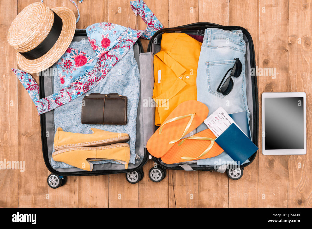 Top view of open luggage full of woman's clothes and other essential ...