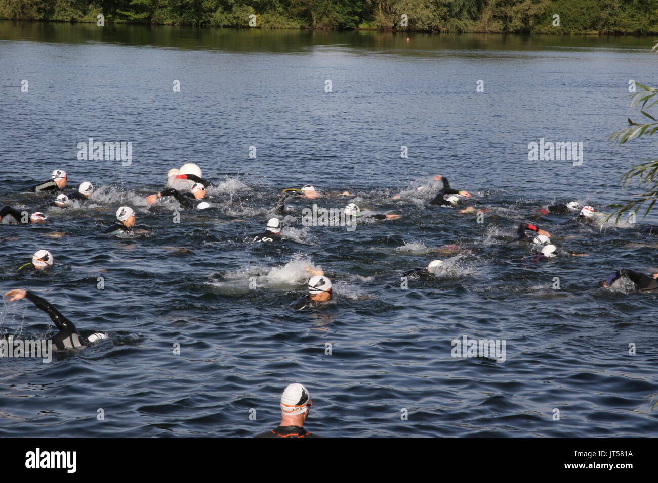 a large group of male swimmers in a lake waiting the start of a ...