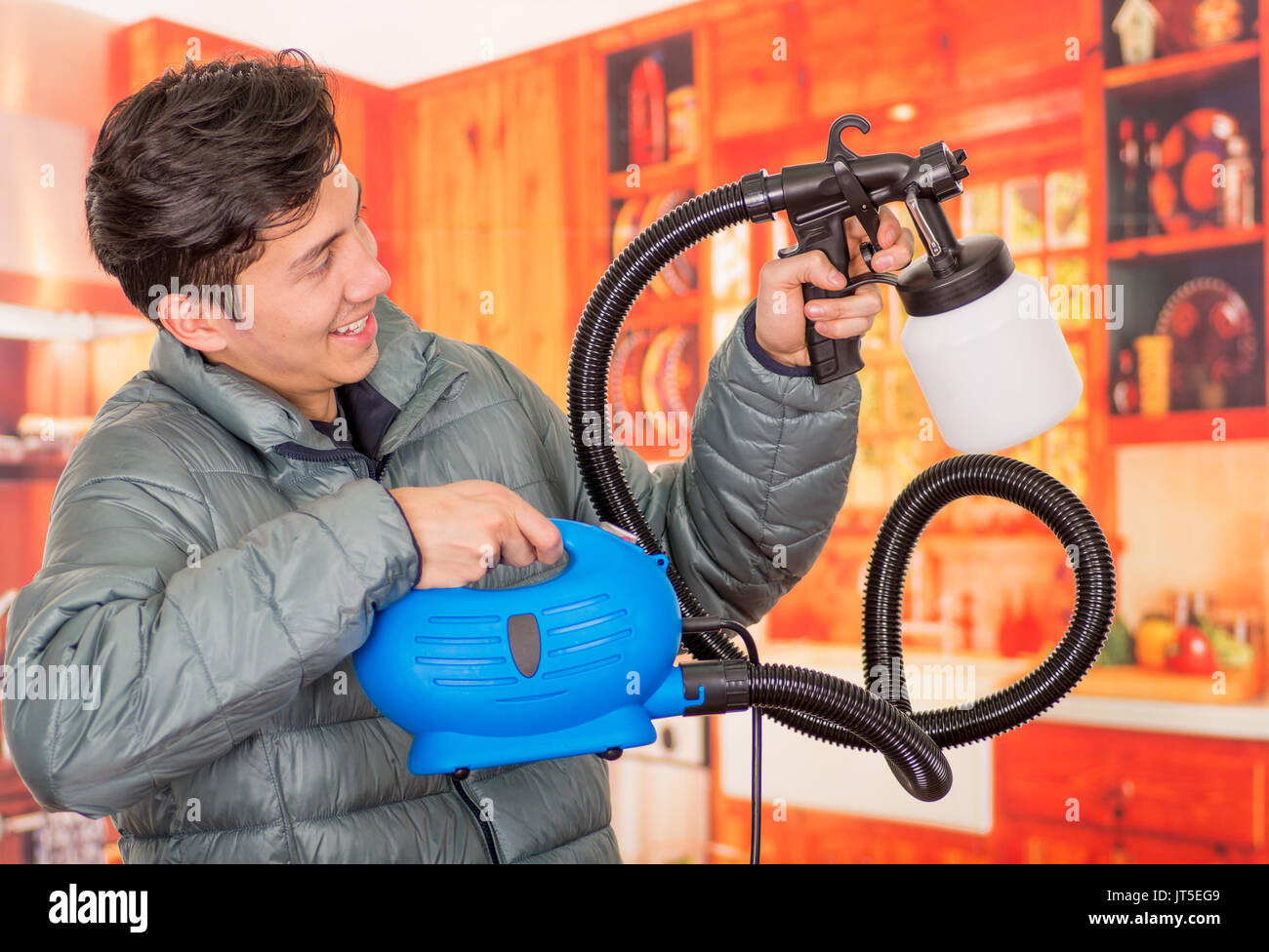Handsome smiling man holding in his hands the painting spray gun, an ...