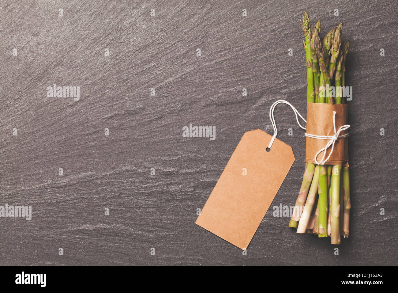 Fresh asparagus tied in a bunch on a rustic slate background with blank ...