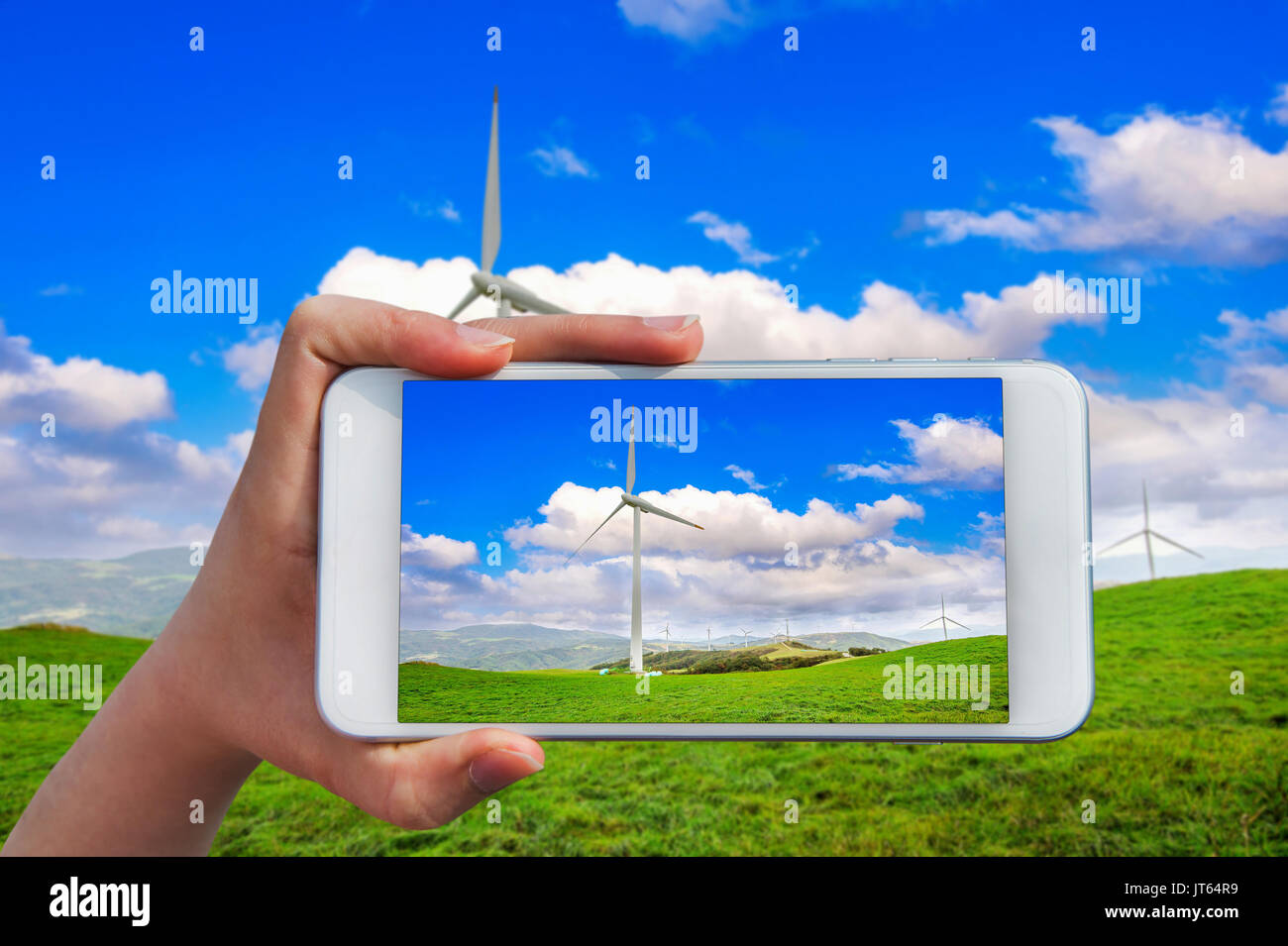Hand holding smart phone take a photo at Wind turbines generating ...