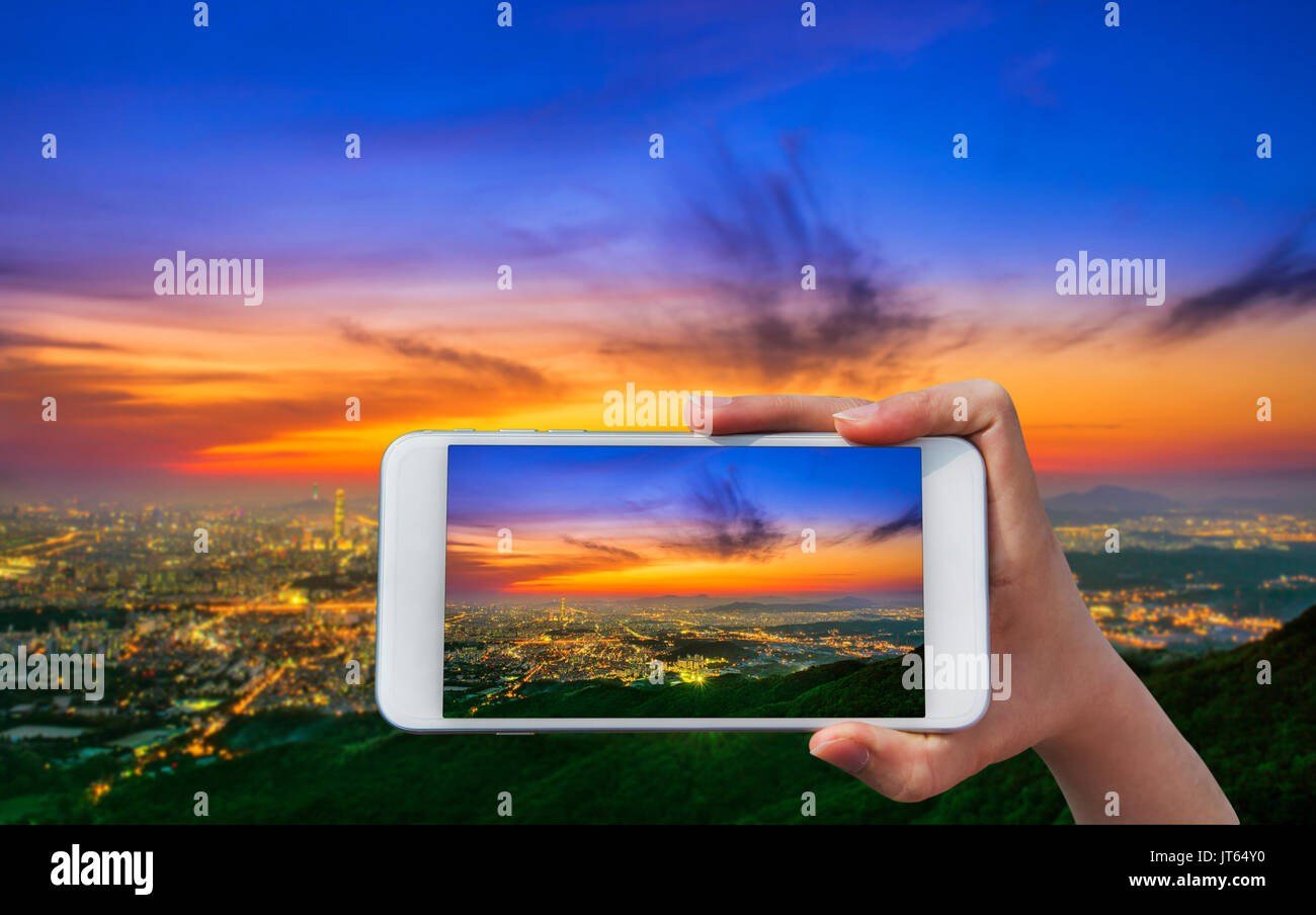 Hand holding smart phone take a photo at South Korea skyline of Seoul ...