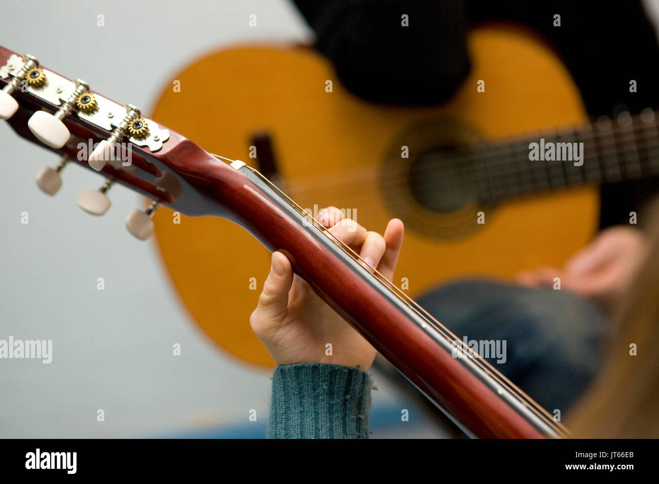 Young girl, teenager, learning how to play the guitar. Hand playing ...