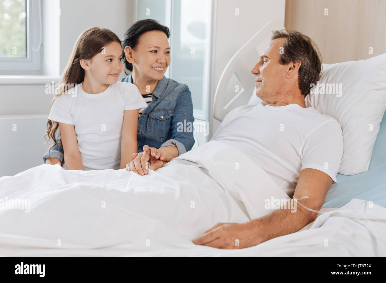 Delighted positive mother and daughter visiting their dad Stock Photo ...