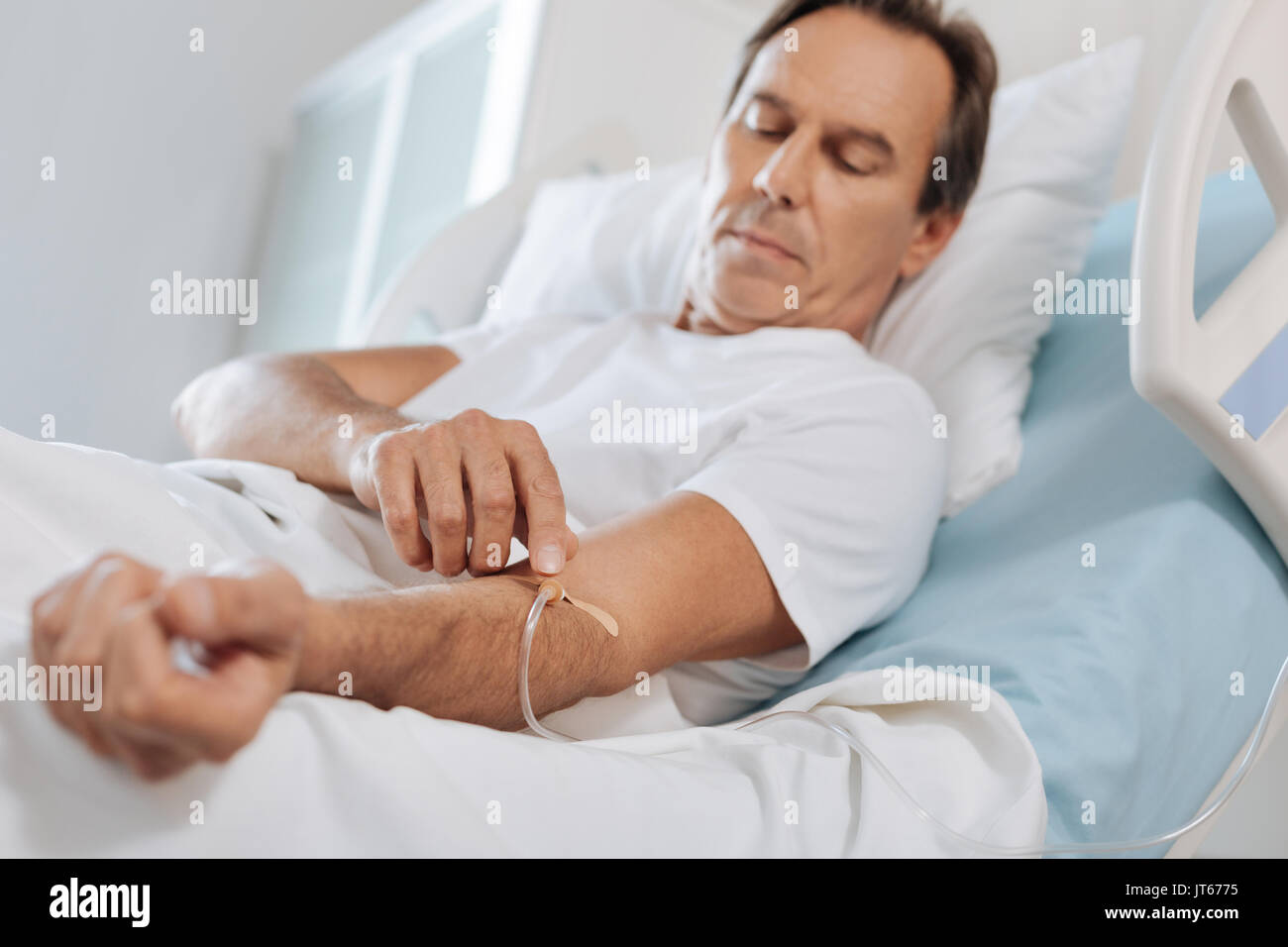 Pleasant nice man looking at his catheter Stock Photo - Alamy Pleasant nice man looking at his catheter Stock Photo - Alamy