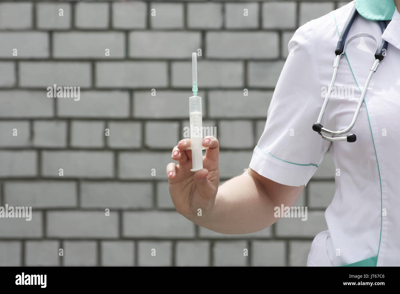 Medicine concept doctor. Injection. On a white brick wall background ...