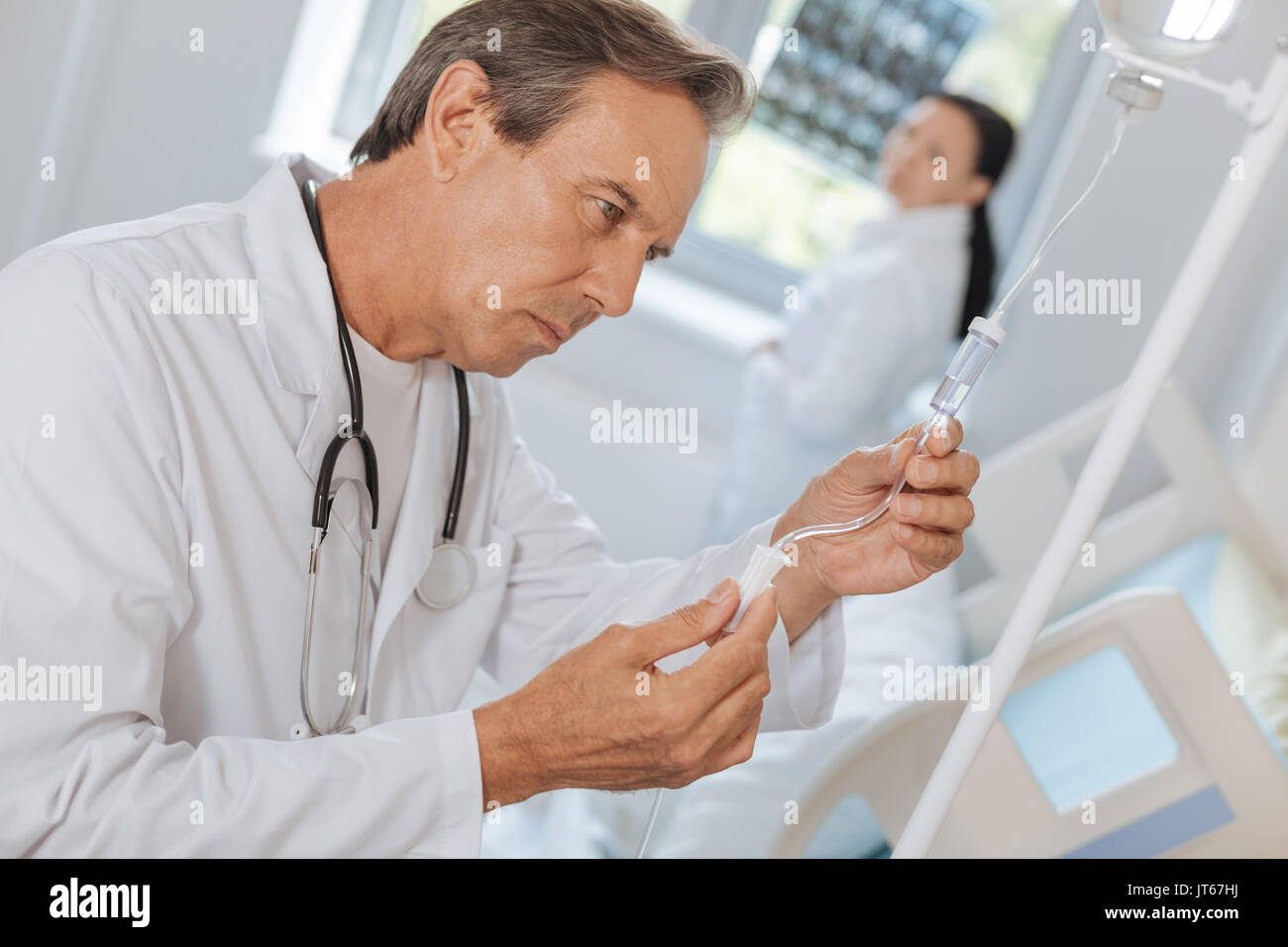 Serious thoughtful doctor holding an IV tube Stock Photo - Alamy