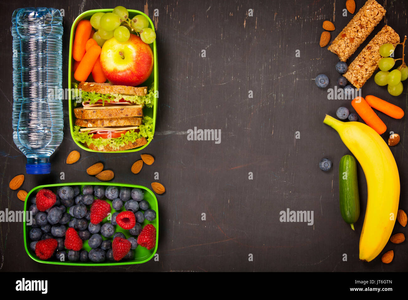 Sandwich, apple, grape, carrot, berry in plastic lunch box and bottle ...