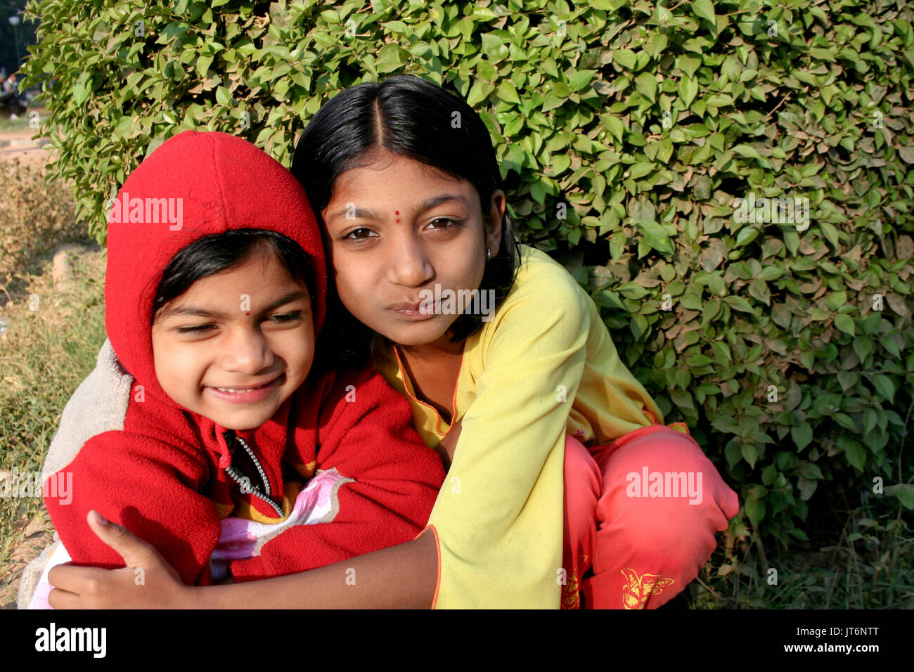 Elder sister affectionately putting her arm over the shoulder of her ...