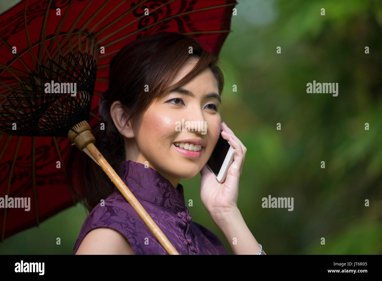 Chinese Woman talking on a Smart Phone and wearing a Cheongsam Chinese ...