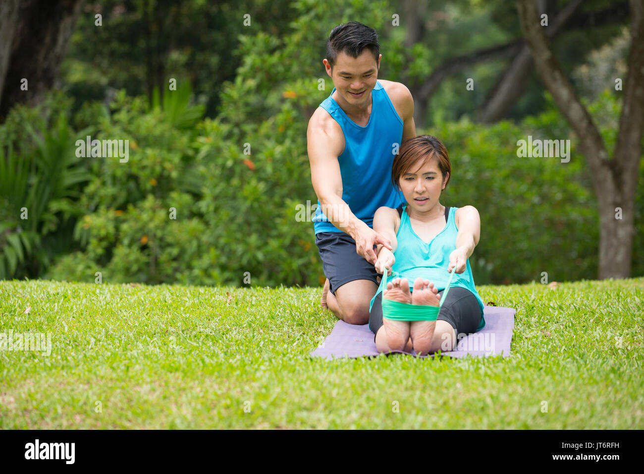 Asian woman with a personal trainer doing exercises outdoors. Action and healthy lifestyle ...