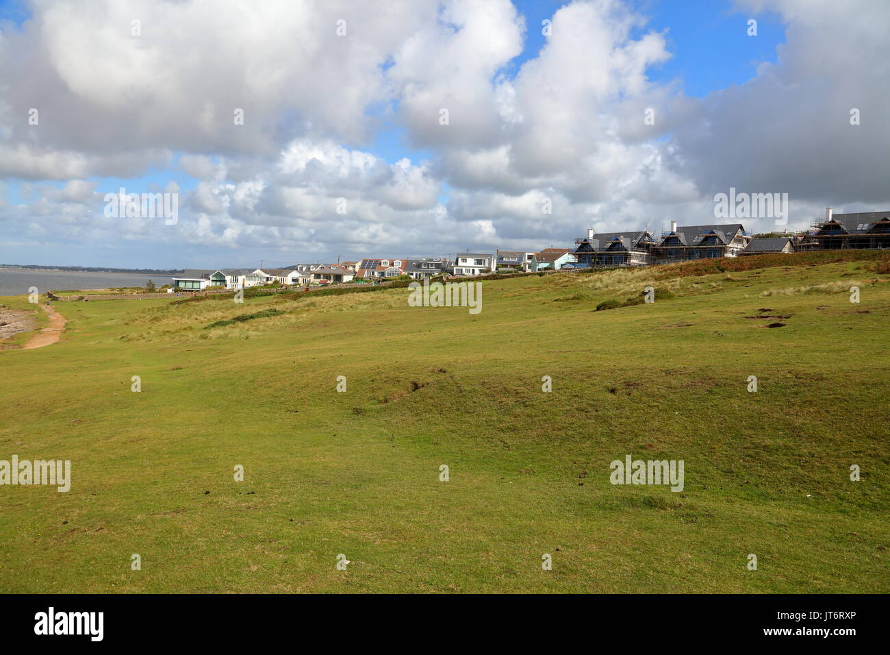 A sloping field beside the beach with some new build houses currently ...