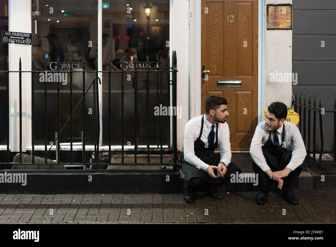 Two waiters taking a rest outside a restaurant on Bateman Street in ...
