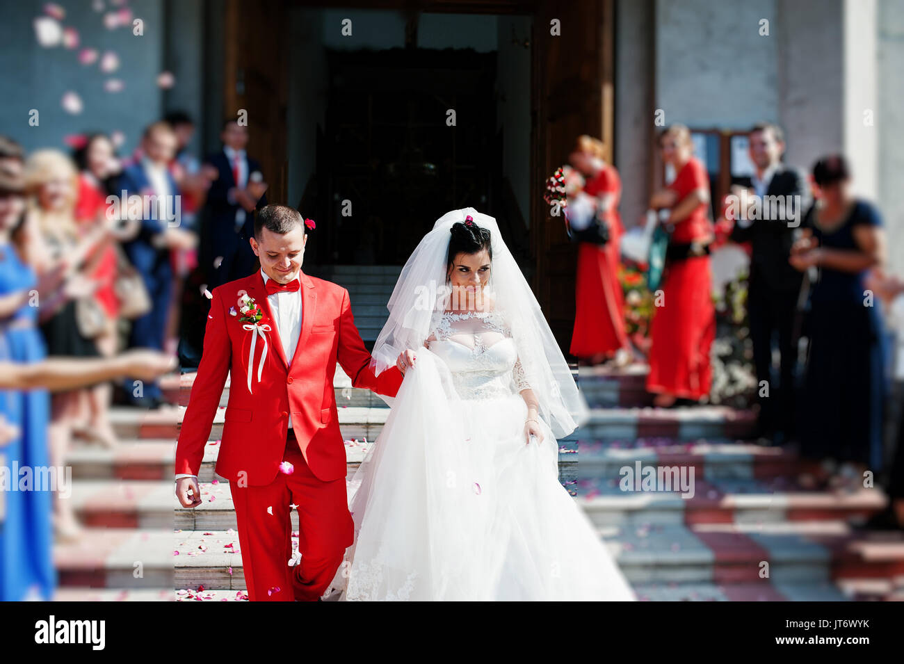 Fabulous wedding couple walking out of the church and people throwing ...