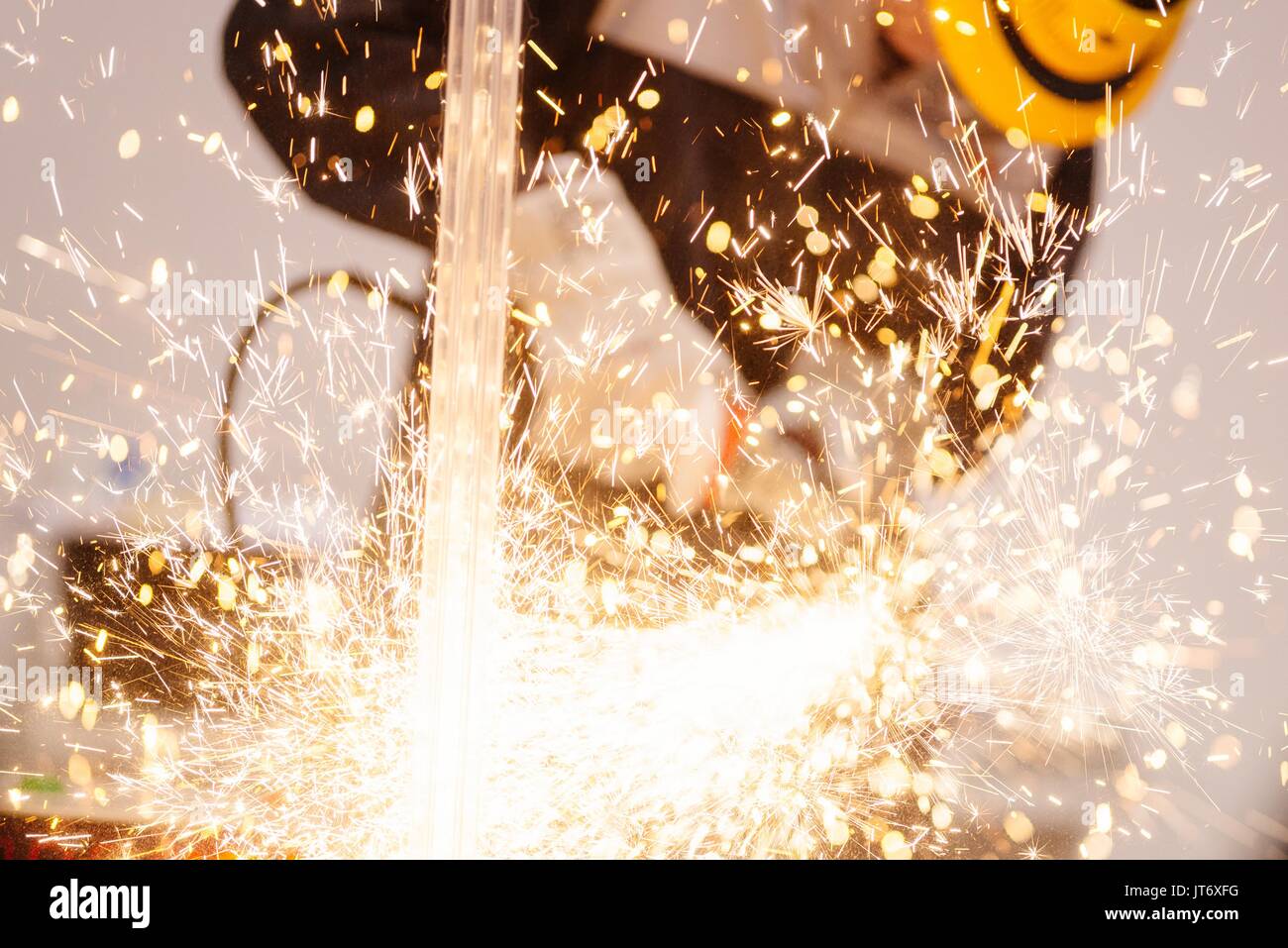 Mechanic in protective gloves cutting metal with red handheld grinder ...