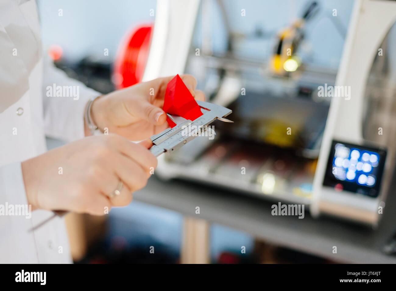 Woman checking the dimensions of the component made in the 3d printer ...